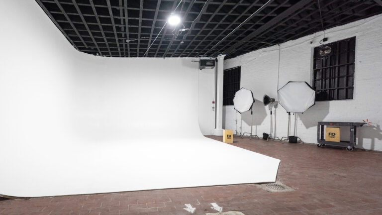 A spacious photo studio for rent with a concrete wall and a piano in ...